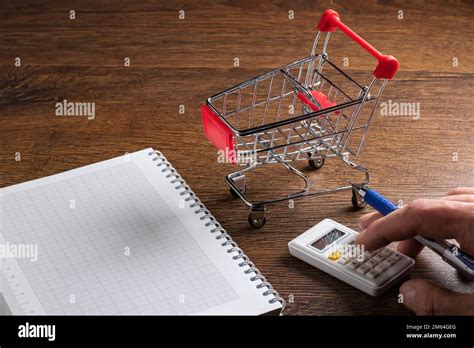 Man Calculates The Budget Shopping Cart A On Table With Calculator And Paper Budget Of Poor