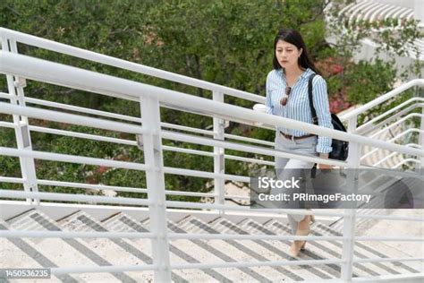 예쁜 아시아 한국 사무실 아가씨의 전체 길이는 낮 동안 도시 거리를 배경으로 가기 위해 커피를 마시며 위층으로 걸어가고 있습니다