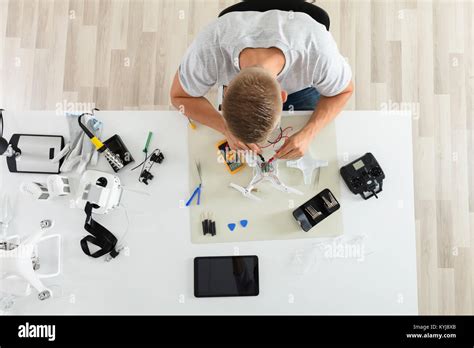 Close Up Of A Man Testing Electric Current Of Disassembled Drone Using Multimeter Tool Stock