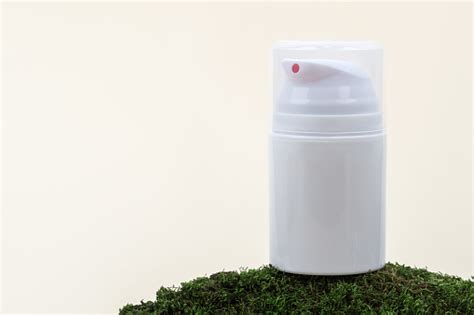 베이지 색 배경에 녹색 이끼에 서 있는 신 크림 케어와 흰색 플라스틱 병 0명에 대한 스톡 사진 및 기타 이미지 0명 개념