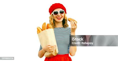 흰색 배경에 고립 된 긴 흰색 빵 바게트가있는 종이 봉지를 들고 빨간 베레를 입은 크로와상을 먹는 초상화 예쁜 여자 흰색 배경에 대한 스톡 사진 및 기타 이미지 Istock