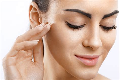 페이셜 케어 크림을 바르고 웃는 여자 피부에 화장품 크림을 가진 젊은 여자의 초상화 부드러운 피부에 미용 제품과 아름 다운