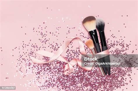 핑크 리본과 홀로그램 반짝이 색종이가있는 다른 화장품 메이크업 브러시는 분홍색 배경에 별 형태로 색종이 플랫은 상단보기 복사 공간을 놓습니다 메이크업 액세서리 휴일 생일