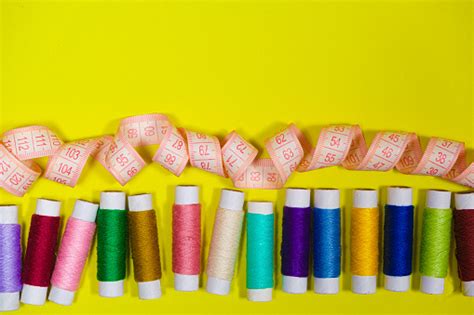 바느질을 위한 여러 가지 색상의 스레드 세트와 노란색 배경의 측정 테이프 상단 보기입니다 개인 장식품에 대한 스톡 사진 및 기타