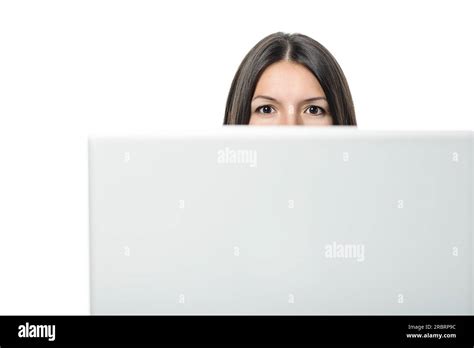Young Woman Looking At Camera With Intelligent Eyes While Hiding Behind The Monitor Of A Desk