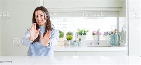 집에서 흰색 테이블에 앉아 아름 다운 젊은 여자의 광각 사진 혐오 표정 불쾌 하 고 혐오 얼굴을 하 고 두려워 혐오 반응 때문에 손을 올려 성가신 개념입니다 냄새 맡기에