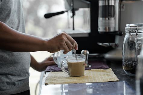 뜨거운 물과 Nworkplace 카페에서 커피와 함께 혼합 하는 숟가락을 사용 하 여 들고 남자 바리 스타의 손 갈색에 대한