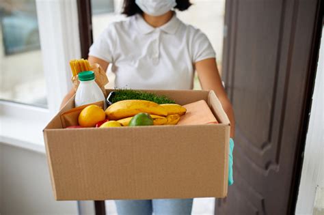 흰색 보호 마스크와 장갑 배달 기부 상자를 입은 자원 봉사 여성 음식과 포장 상자가있는 택배 비접촉식 배달 서비스 검역 전염병