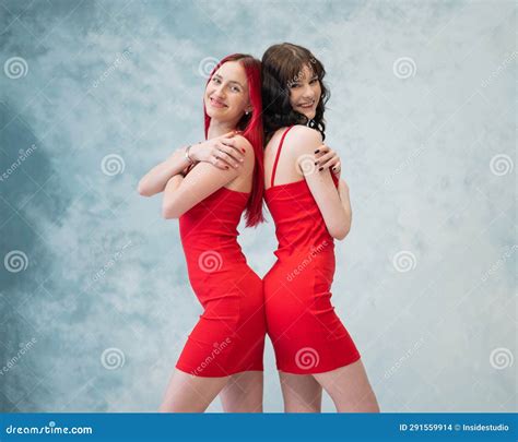 Portrait Of Two Women Dressed In Identical Red Dresses And Standing Back To Back Lesbian