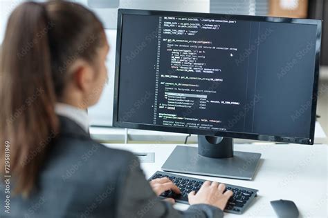 Over Shoulder View Of Female Programmer Using Computer With Code Lines On Screen In IT Company