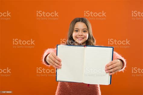 이것 좀 확인해 주세요 소녀는 책 오렌지 배경을 보유하고 있습니다 어린이는 책이나 메모장의 열린 페이지를 표시합니다 서점 컨셉