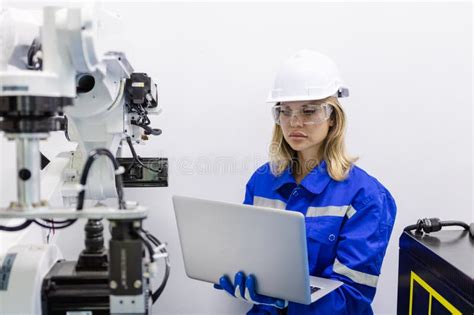 female technician engineer using laptop checking automation robotics at industrial modern