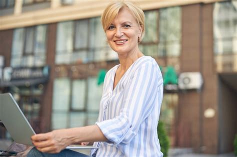 Premium Photo Portrait Of A Pleased Blonde Mature Caucasian Lady With A Computer Posing For