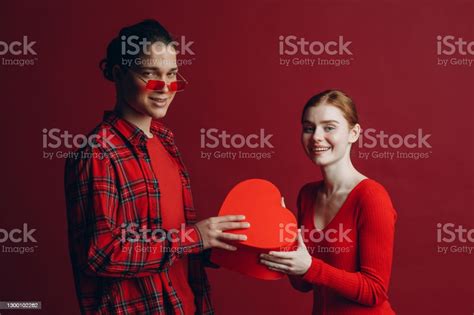 젊은 남자는 빨간 배경 스튜디오에서 발렌타인 데이에 그의 여자 친구에게 하트 모양의 상자를 제공합니다 18 19세에 대한 스톡 사진 및 기타 이미지 Istock