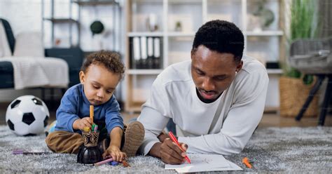 사랑하는 아프리카계 미국인 아버지와 귀여운 아들이 바닥에 함께 누워 앨범에 화려한 연필로 그림을 그립니다 집에서 가족과 함께하는 시간 공생의 개념 사진