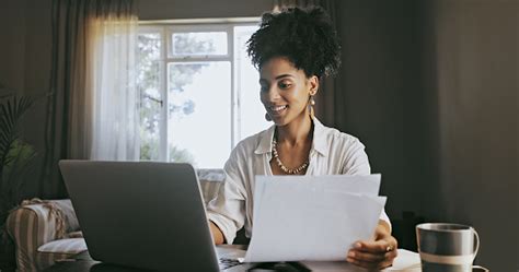 노트북 문서 및 원격 작업 그녀의 홈 오피스에서 보고서에 대한 직장에서 비즈니스 흑인 여성과 함께 거실에서 일하는 프리랜서 여성 기업가와 함께 컴퓨터 검색 및 서류 작업