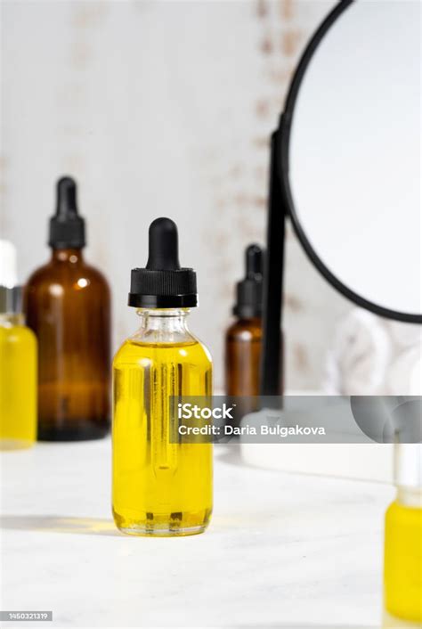 욕실의 화장 테이블에 혈청 오일과 거울이 담긴 병 피부와 모발 관리를위한 점 적기가있는 유리 병에 담긴 유기농 화장품 세트 자기