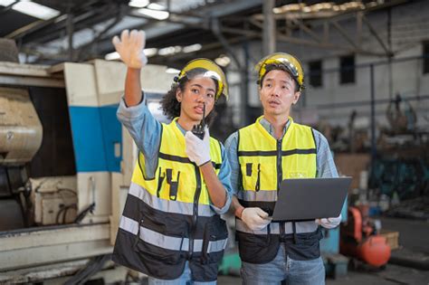 전문 엔지니어링 작업자가 창고 공장을 걷고 체크인합니다 관리자는 내부 감사를 위한 검사 보고서 논문에 대해 논의합니다 제조에 대한 품질 보증 컨셉 엔지니어 운영 2명에 대한