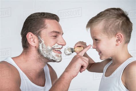 Side View Of Happy Father And Son Shaving Together Isolated On Grey