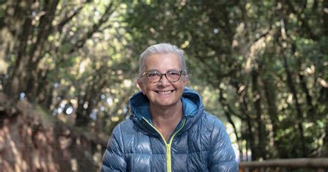 흰 머리와 안경을 쓴 쾌활한 미소를 짓는 노인 여성이 숲 속 여행에서 자유와 자연을 즐기고 있다 사진 Unsplash의 나무 이미지