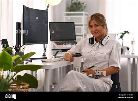 Young Female Developer Sitting Front Of Computers With Coded Data On