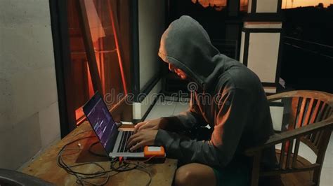 downshifter hacker programmer in a hood creates a new program with