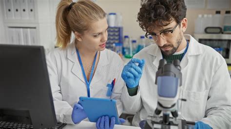 A Woman And Man Scientists Collaborating In A Laboratory Analyzing Samples Under A Microscope