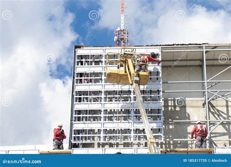 Construction Workers On Construction Site Making External Cladding