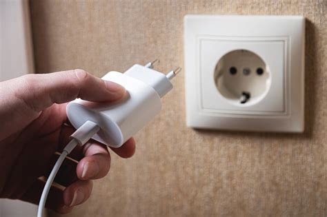 손이 켜지고 벽에 있는 전기 콘센트의 충전기가 꺼집니다 여자의 손에 있는 전화를 위한 흰색 충전기 클로즈업 개념에 대한 스톡 사진 및 기타 이미지 Istock