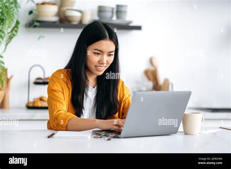 Positive Friendly Smiling Chinese Girl Freelancer Programmer Manager Sitting At The Table