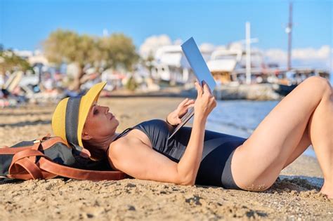 Premium Photo Mature Woman Sunbathing On The Beach In Hat With Laptop