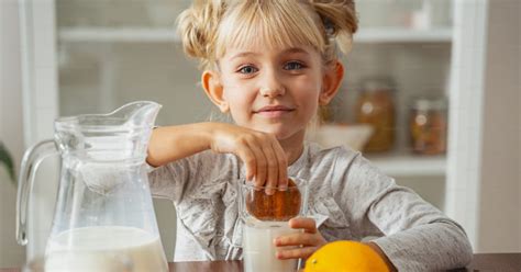 우유와 페이스트리 한 잔을 들고 식탁에 앉아 웃고 있는 사랑스러운 어린 소녀 스톡 사진 사진 Unsplash의 건강한 식생활 이미지