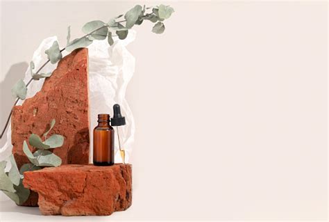 빨간 돌에 드롭퍼 세럼과 구겨진 종이와 베이지 색 배경으로 갈색 유리 병을 모으세요 잔인 공간을 복사합니다 산 성 박리 페이스