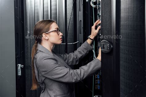 Businesswoman In Glasses Looking At Server Rack In Data Center Stock Photo By LightFieldStudios