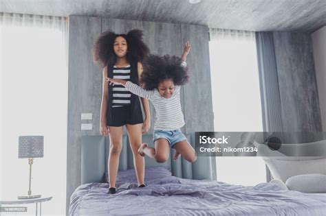 귀여운 어린 아이들이 홈에서 침대에서 뛰어 내립니다 집에서 행복한 가족 자매는 침대에 뛰어 올라 웃었다 2 3 살에 대한 스톡 사진 및 기타 이미지 Istock