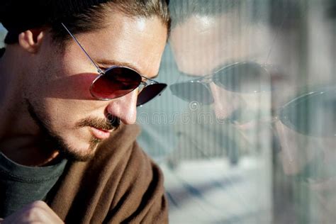 Красивый парень в солнечных очках на улицах большого города Отражение