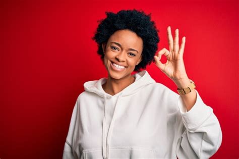 젊은 아름 다운 아프리카 계 미국인 Afro 스포츠 여자 곱슬 머리를 입고 스포츠웨어 미소 긍정적인 하 고 확인 기호 와 손과 손가락 성공적인 식입니다 표지판에 대한 스톡