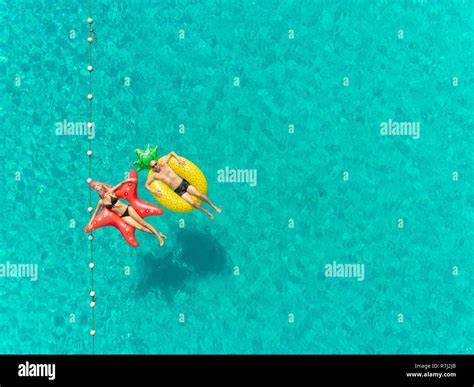 Aerial View Of Man And Woman Floating By String Buoy On Inflatable