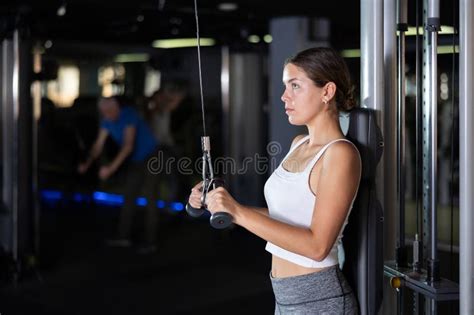Athletic Girl Work Out Muscles Of Arms And Shoulders On Rope Loop