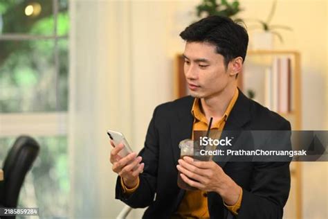 아이스 커피를 손에 들고 현대적인 사무실에서 스마트폰을 사용하는 잘생긴 사업가 25 29세에 대한 스톡 사진 및 기타 이미지 25 29세 30 34세 Brand