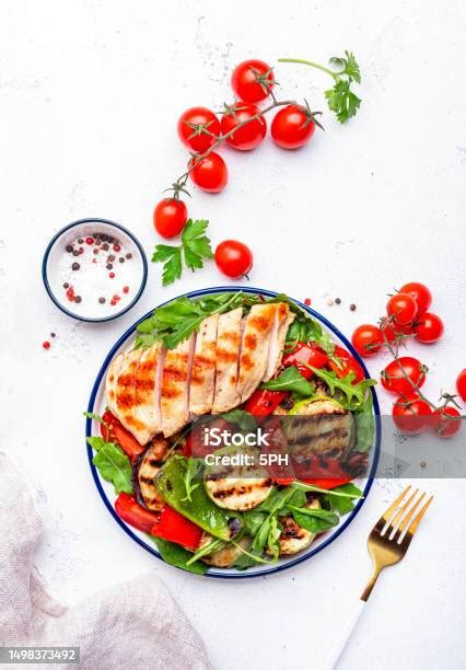 시금치와 루꼴라를 곁들인 구운 닭고기와 야채 샐러드 파프리카 호박 가지 하얀 테이블 배경에 토마토 탑 뷰 굽기에 대한 스톡 사진