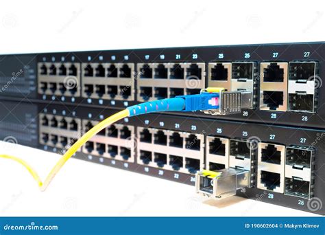 Two Managed Stackable Gigabit Ethernet Switches With A Connected Optical Wires Are On A White