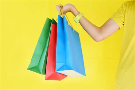 노란색 배경에 고립 된 쇼핑 백을 들고 예쁜 아이 소녀 손 아시아 젊은 여자 행복 한 여름 쇼핑과 휴일을 즐긴다 가방에 대한