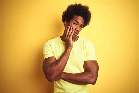 고립 된 노란색 배경 위에 서있는 아프로 머리를 가진 아프리카 계 미국인 남자는 피곤하고 교차 된 팔로 우울증 문제로 지루해 보입니다 T 셔츠에 대한 스톡 사진 및 기타