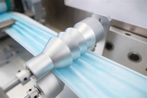 공장에서 제조되는 의료 얼굴 마스크의 클로즈업 과정 호흡기 의료 용 마스크를 대량으로 만드는 자동화 된 기계 0명에 대한 스톡