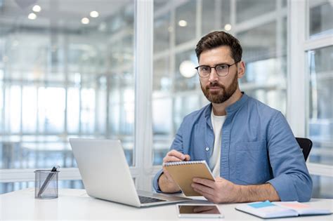 노트북을 손에 들고 진지하고 자신감 넘치는 남자 직장 사무실 안에서 노트북으로 일하는 사업가 카메라를 바라보는 모습 35 39세에 대한 스톡 사진 및 기타 이미지 Istock
