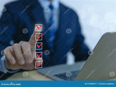 Businessman Hand Holding A Pen Ticking A Red Checkmark On A Box In The