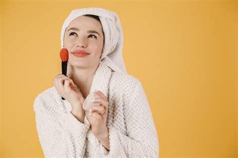 Chica en bata de baño se maquilla ella misma Foto Gratis