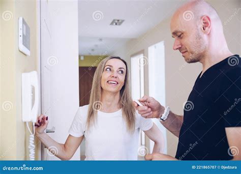 A Handsome Man Explains To The Woman How To Handle The Alarm Protection Against Burglars Stock
