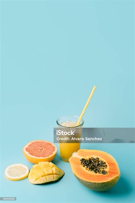 파파야 망고 레몬 자몽 푸른 배경에 신선한 이국적인 과일에 짚 과일 주스 의 유리 여름과 건강한 음식의 개념 복사 공간이 있는